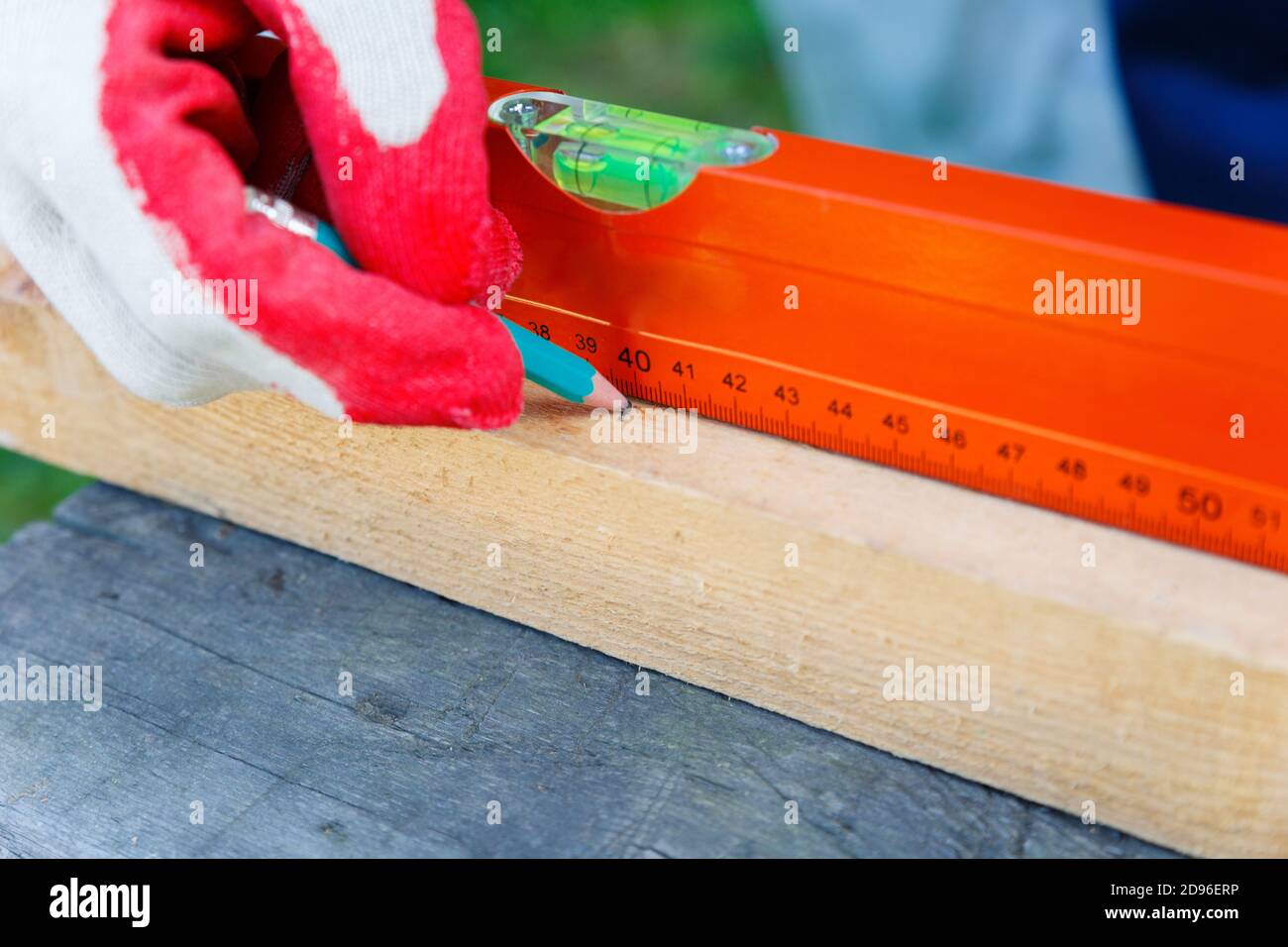 The carpenter's hands in work gloves draw a line with a pencil along ...