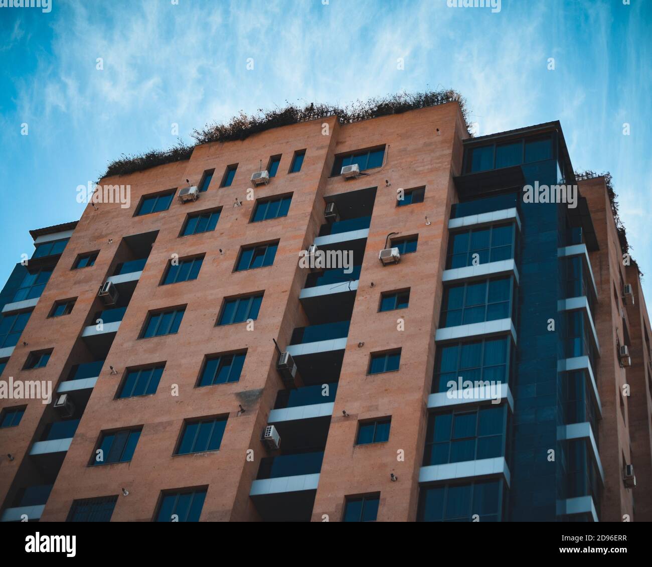 Low angle shot of a red tuff stone building with air conditioning units ...