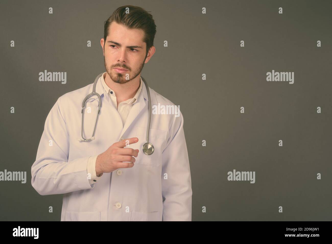 Young handsome bearded man doctor against gray background Stock Photo ...