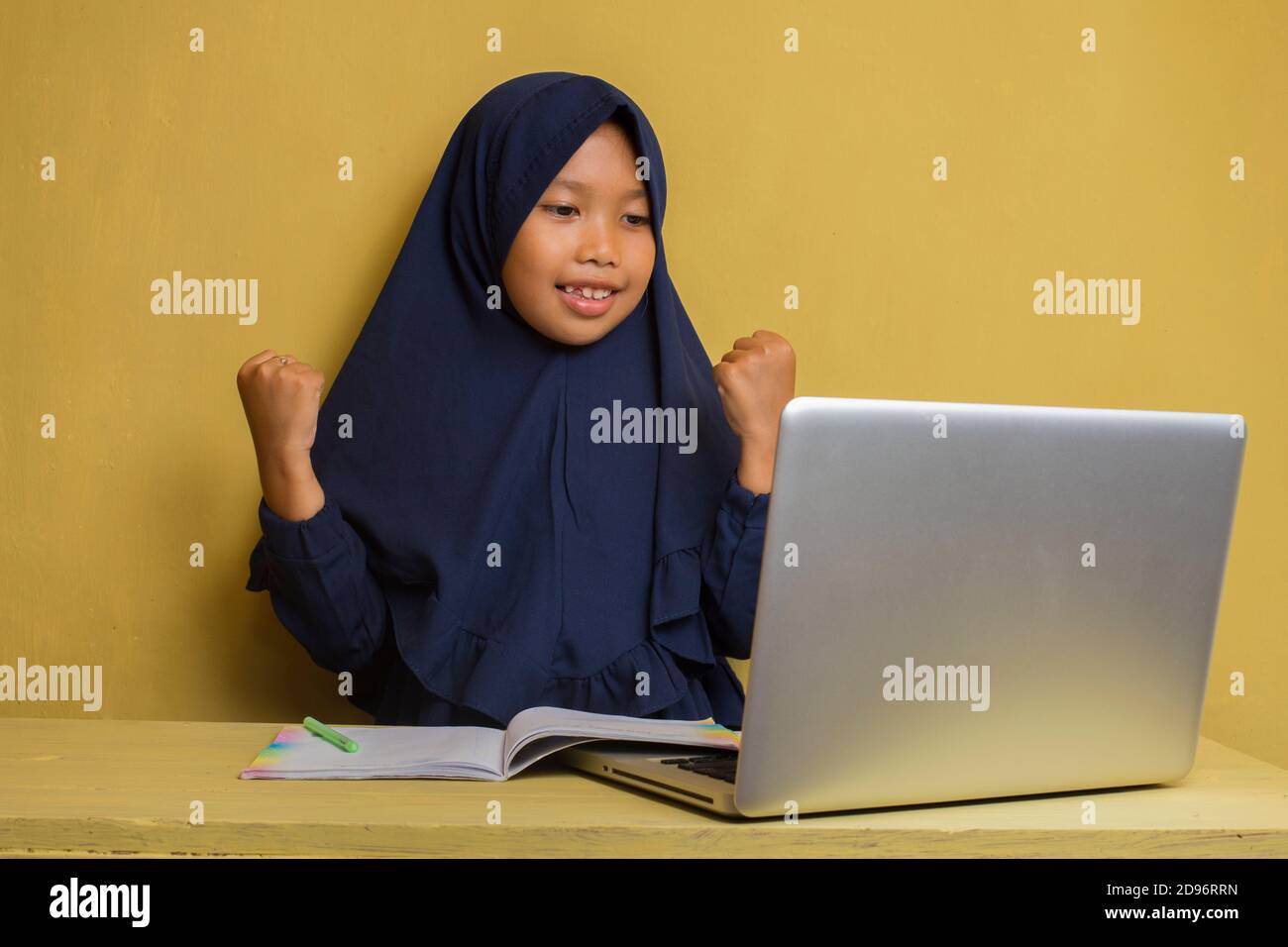 Happy Little asian muslim hijab girl using her laptop computer Stock ...
