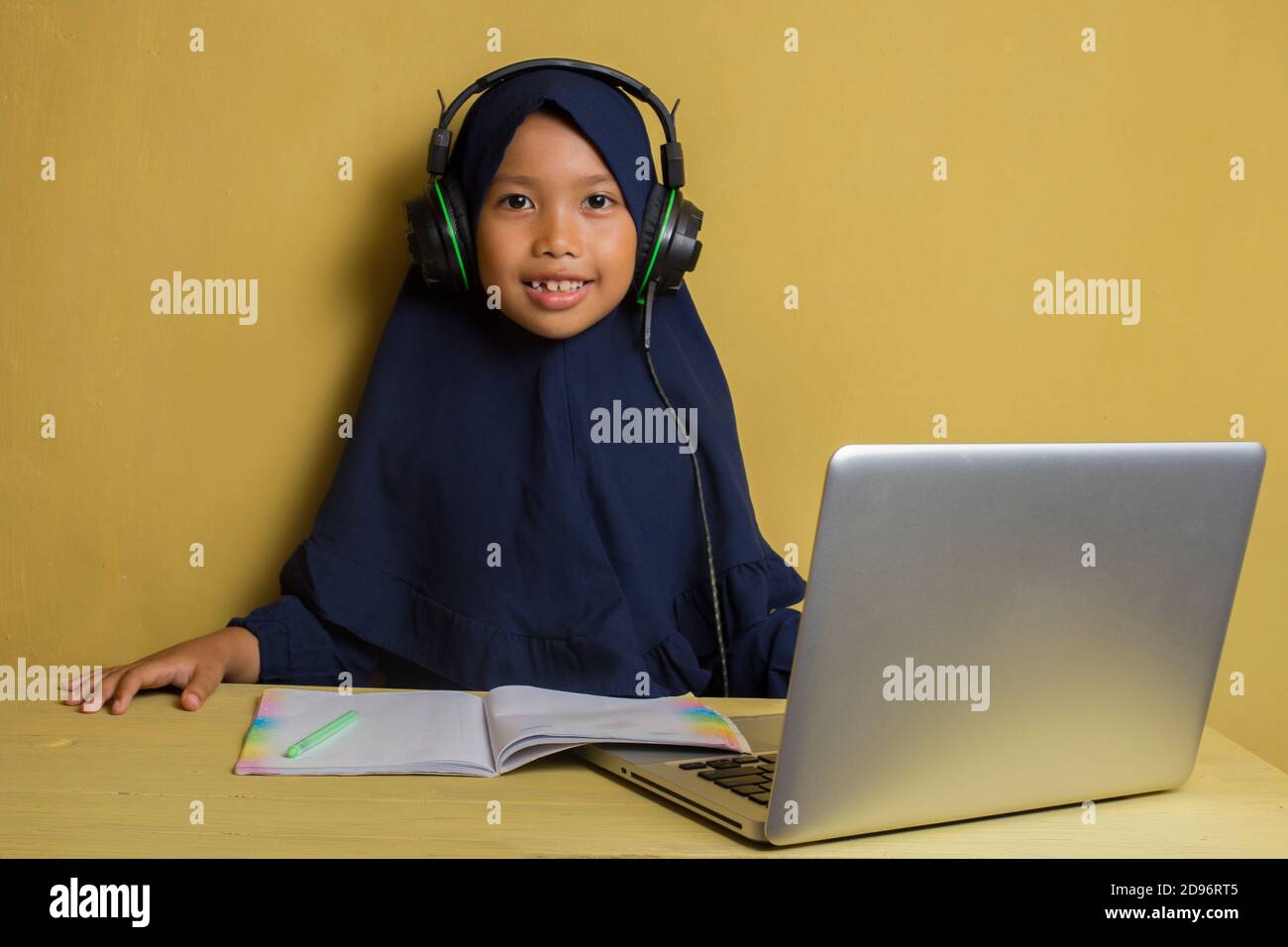 Happy Little asian muslim hijab girl using her laptop computer Stock ...