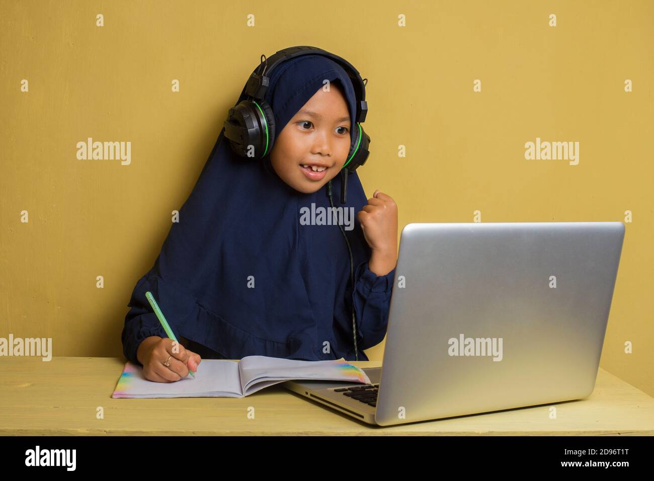 Happy Little asian muslim hijab girl using her laptop computer Stock ...