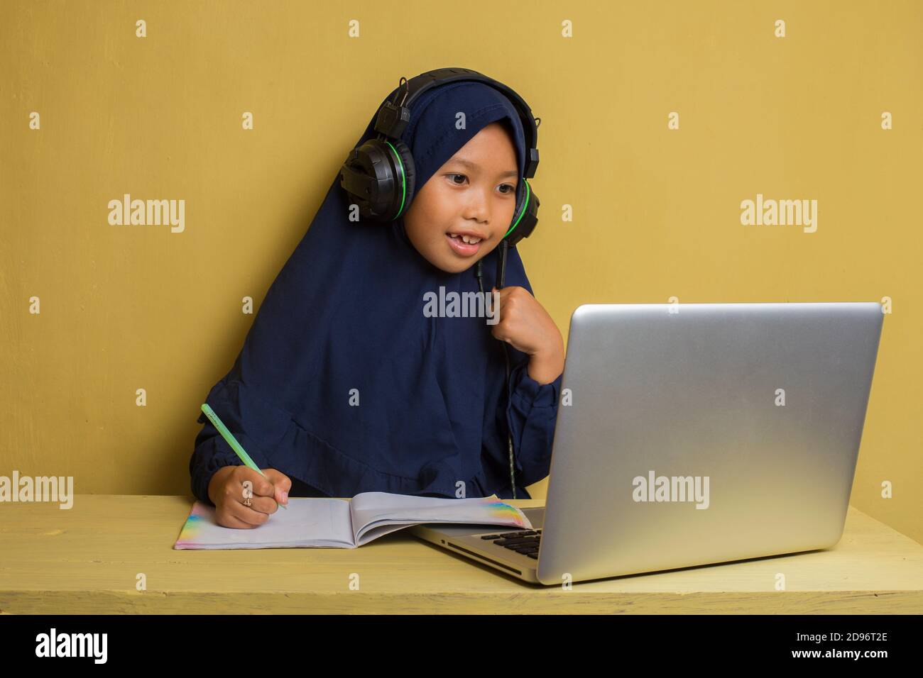 Happy Little asian muslim hijab girl using her laptop computer Stock ...