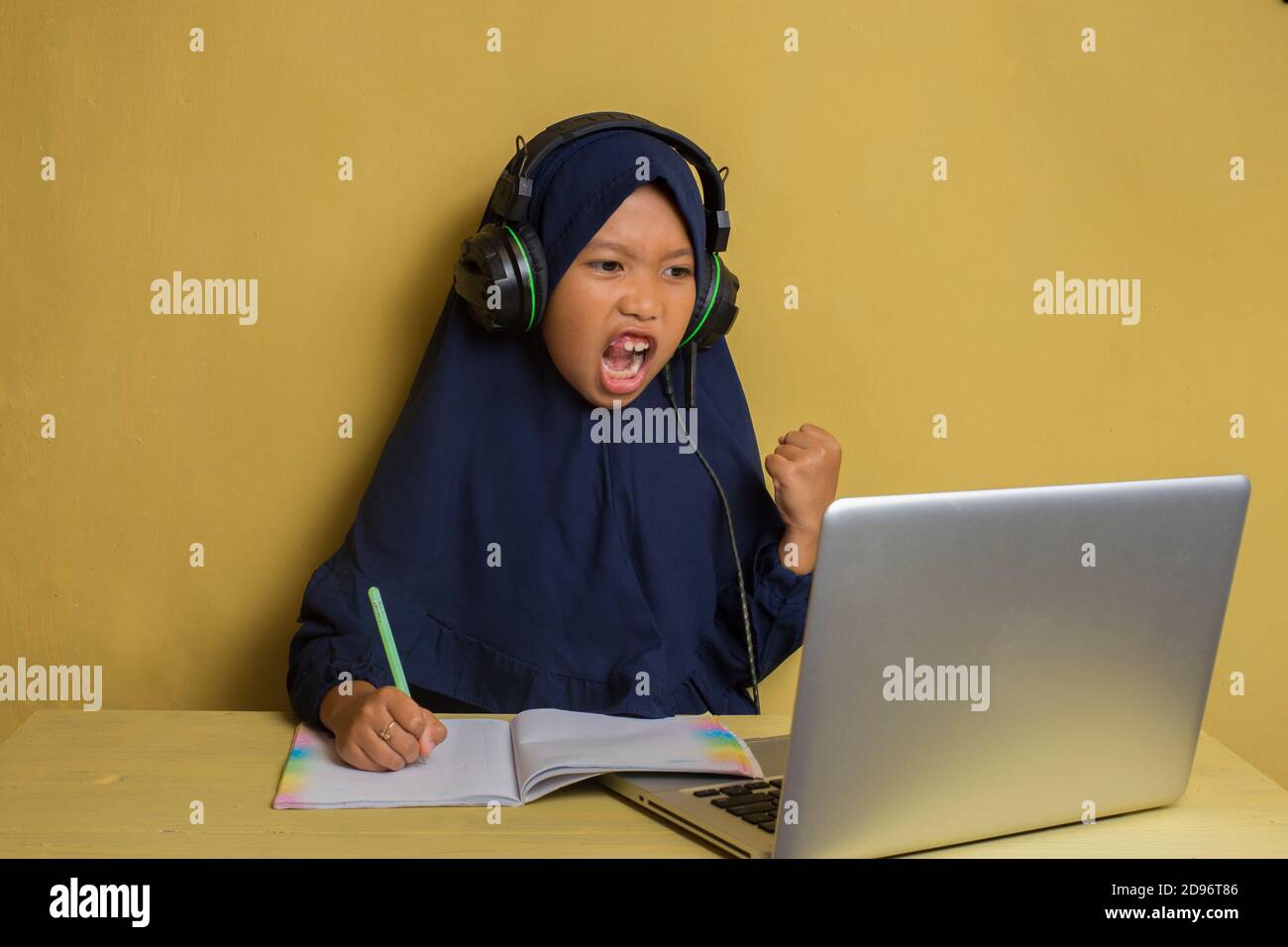 Happy Little asian muslim hijab girl using her laptop computer Stock ...