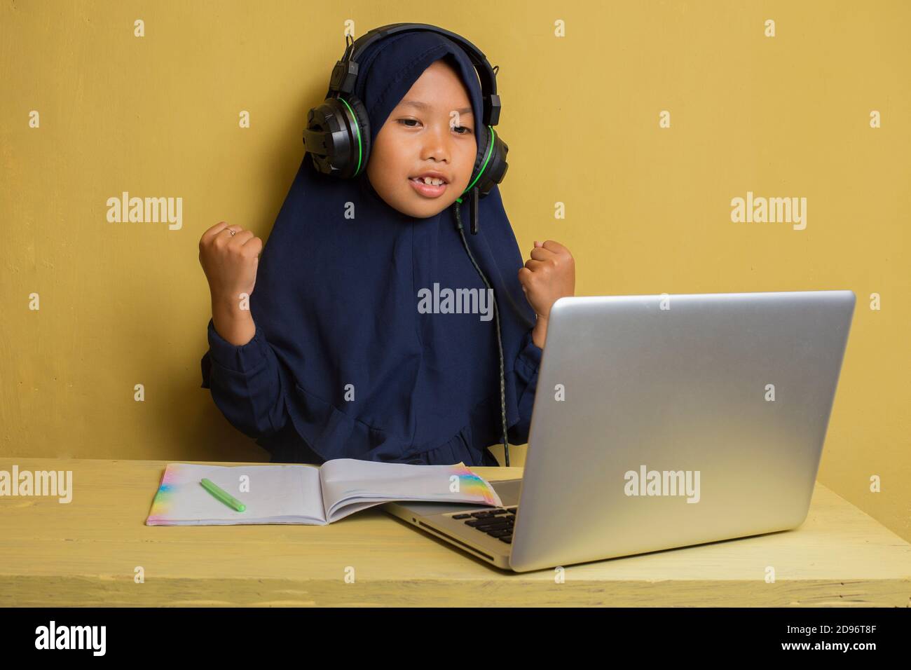 Happy Little asian muslim hijab girl using her laptop computer Stock ...
