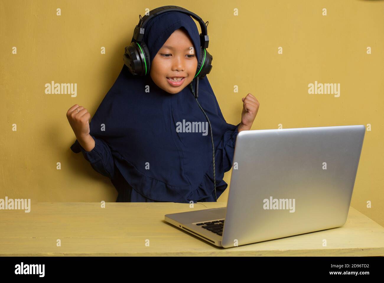 Happy Little asian muslim hijab girl using her laptop computer Stock ...