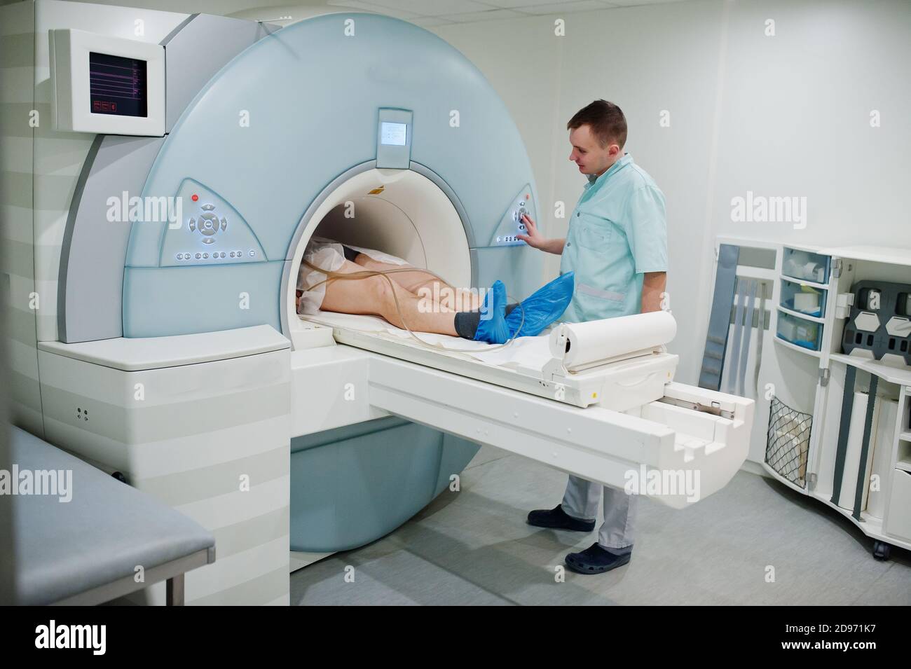 Male doctor turns on magnetic resonance imaging machine with patient ...