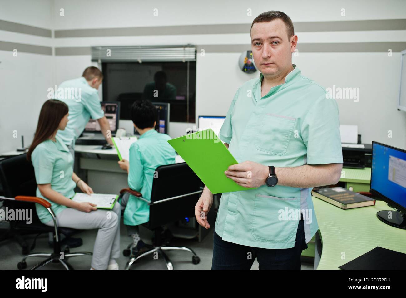 Medical theme .Portrait of male doctor with clipboard against group of ...
