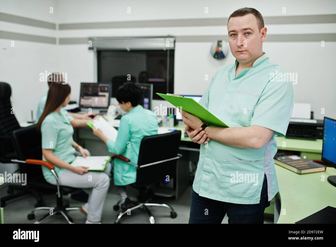 Medical theme .Portrait of male doctor with clipboard against group of ...