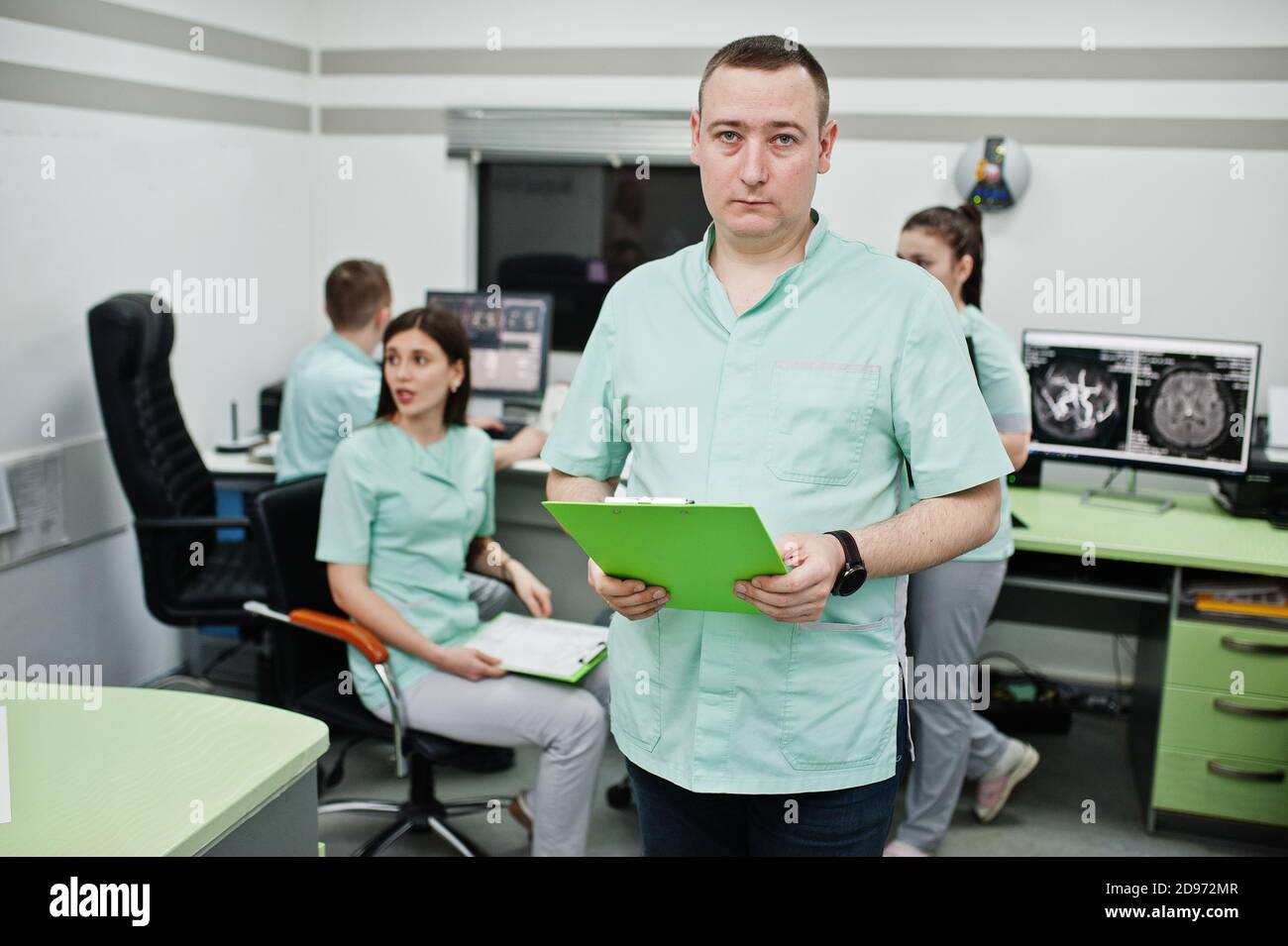 Medical theme .Portrait of male doctor with clipboard against group of ...