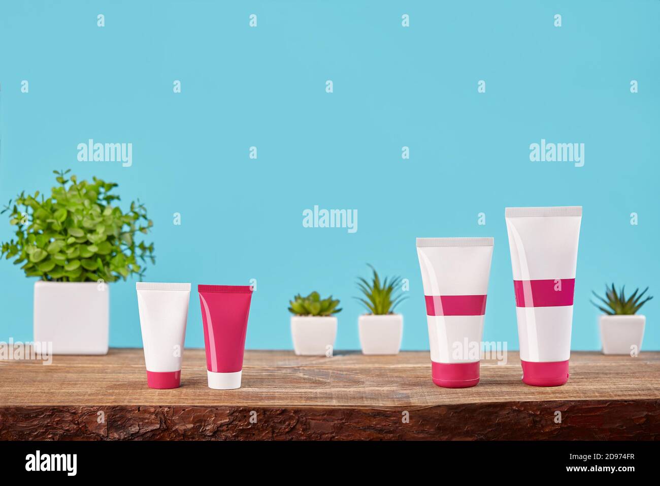 Four colorful no label different sized tubes on wooden tabletop against ...