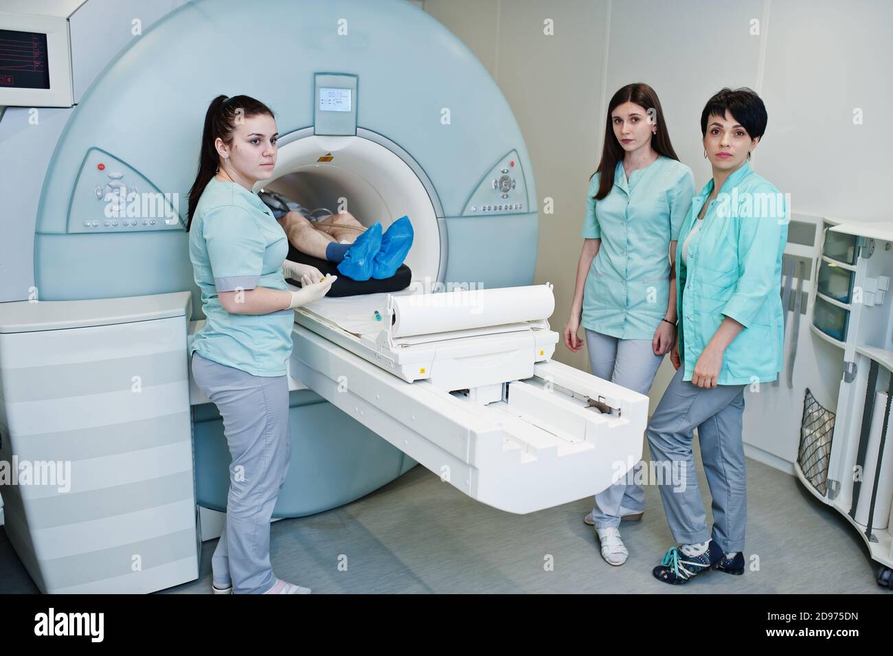 Three female doctors near magnetic resonance imaging machine with ...