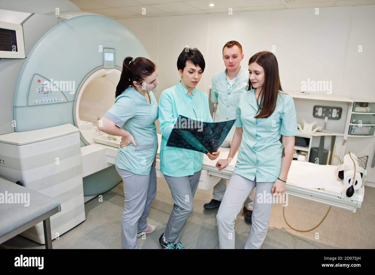 Group of doctors near magnetic resonance imaging machine at hospital ...