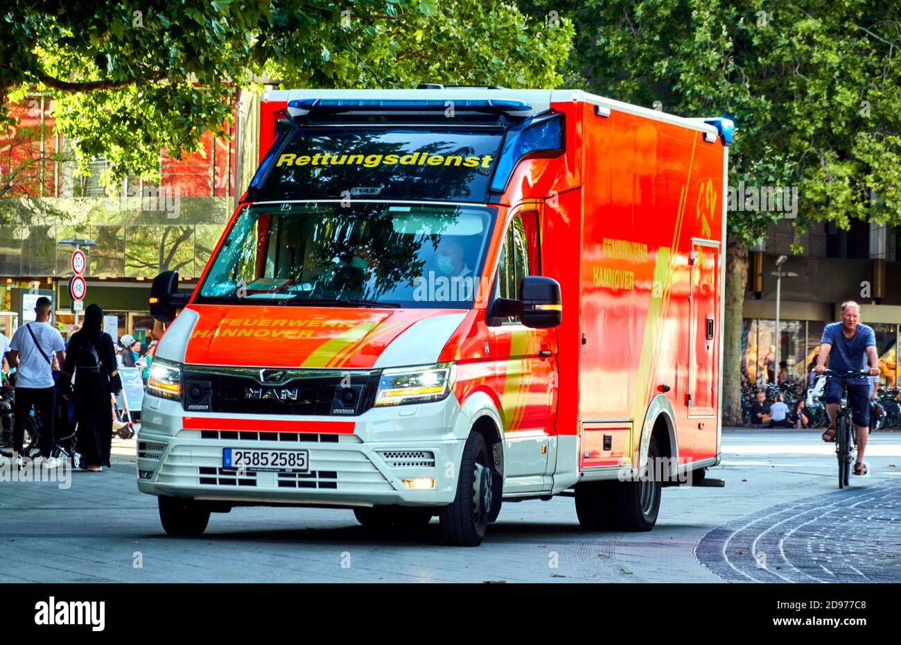 Red ambulance of the rescue service drives through the pedestrian zone ...