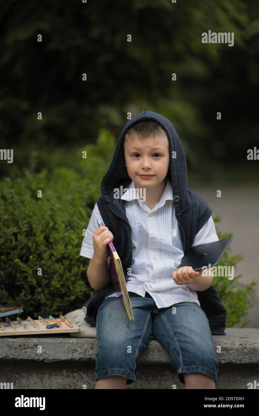 sad boy near school with a tablet and a book cums outside the school on ...