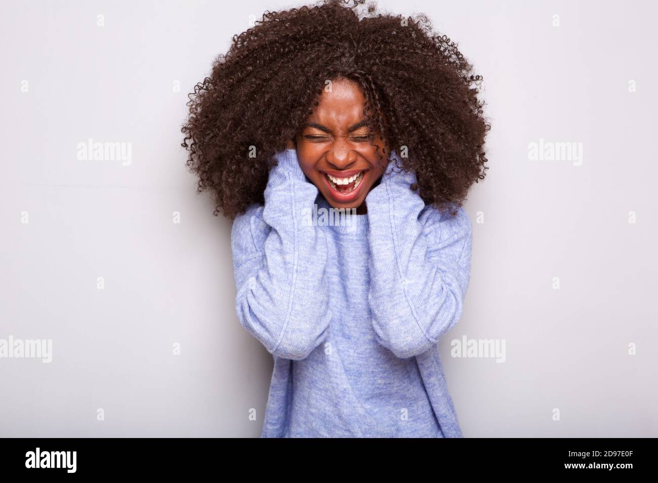 Portrait of young african woman covering her ears and screaming loudly ...
