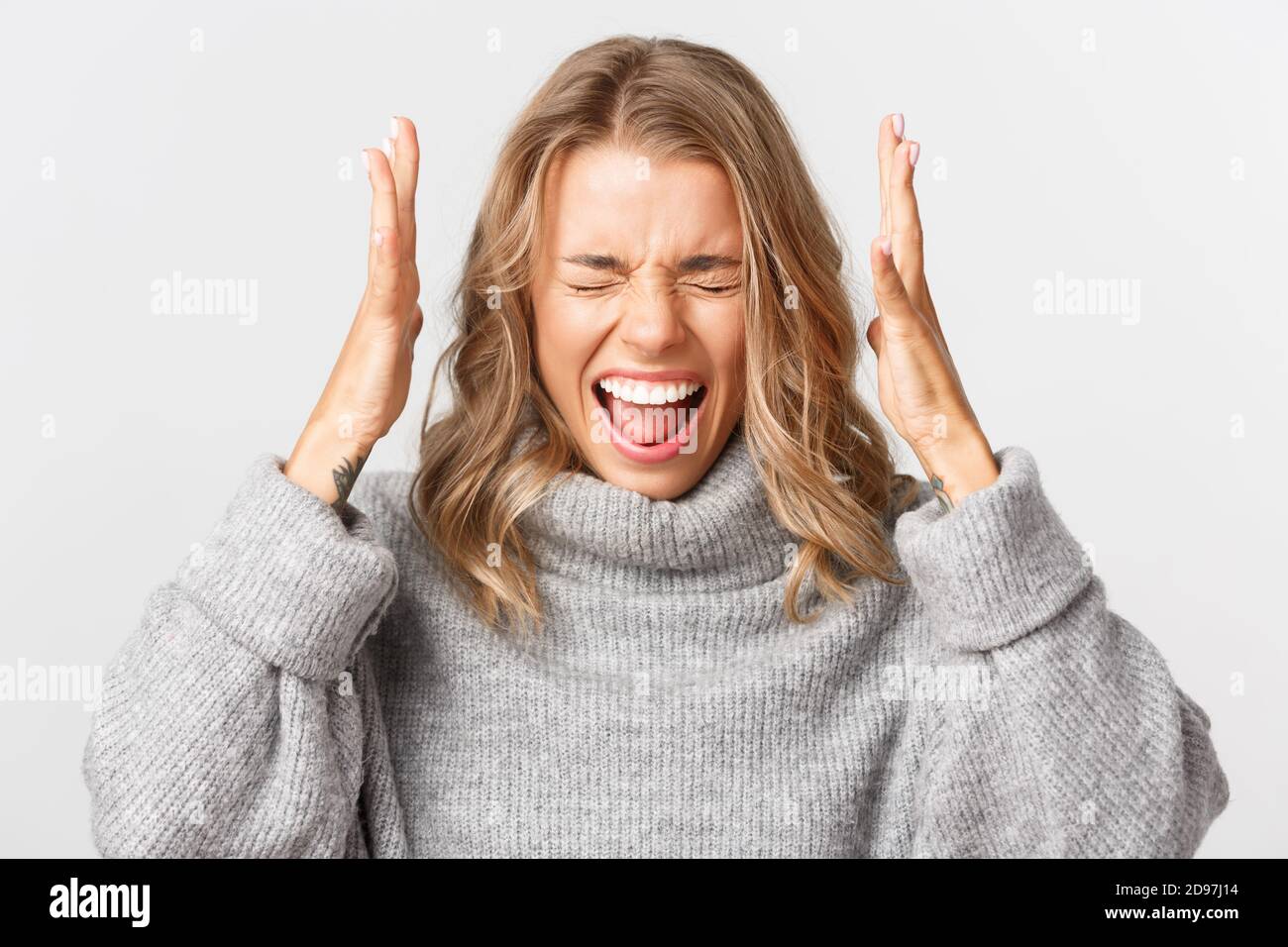 Close-up of angry blond girl in grey sweater, shaking hands distressed ...