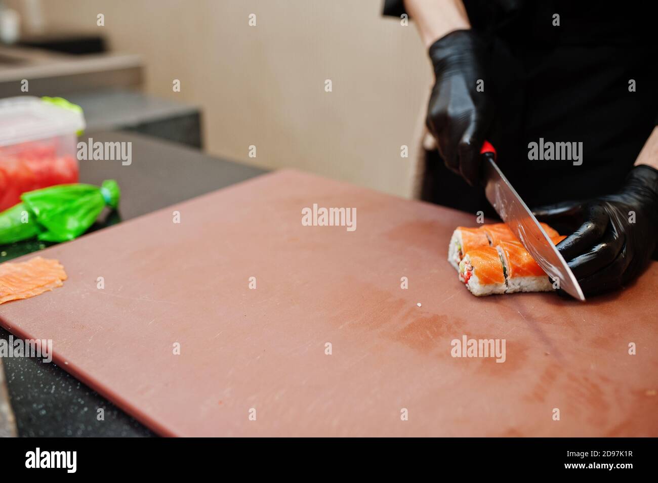 Close up hands of professional chef wear in black gloves making sushi ...