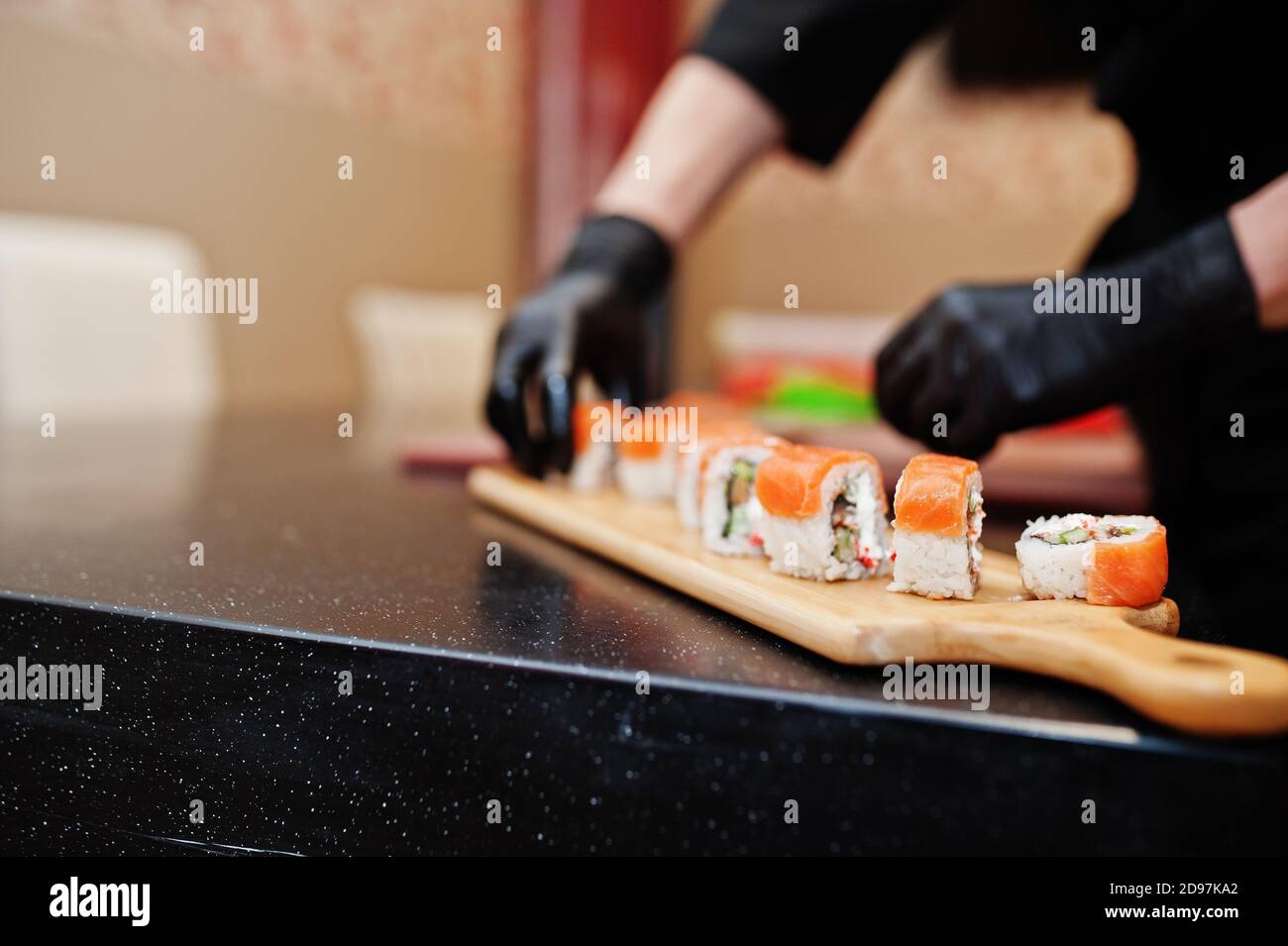 Close up hands of professional chef wear in black gloves making sushi ...