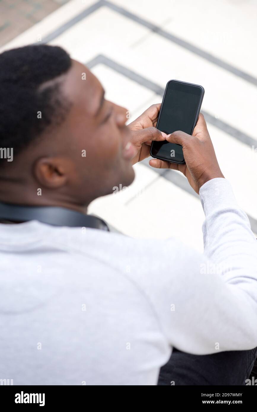 Portrait from behind of young black man holding mobile phone Stock ...