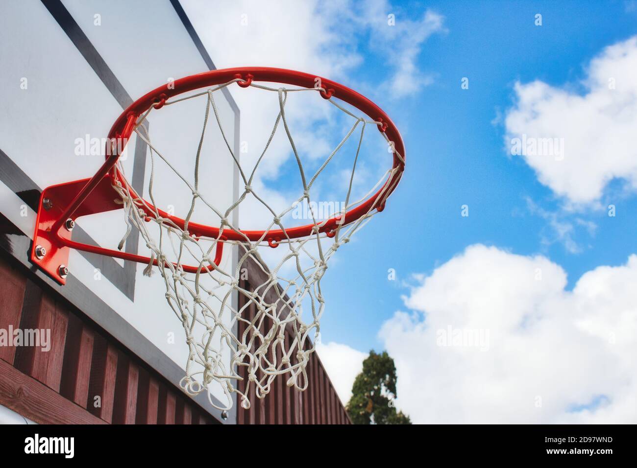 Basketball hoop with netting from underneath with a blue sky background ...