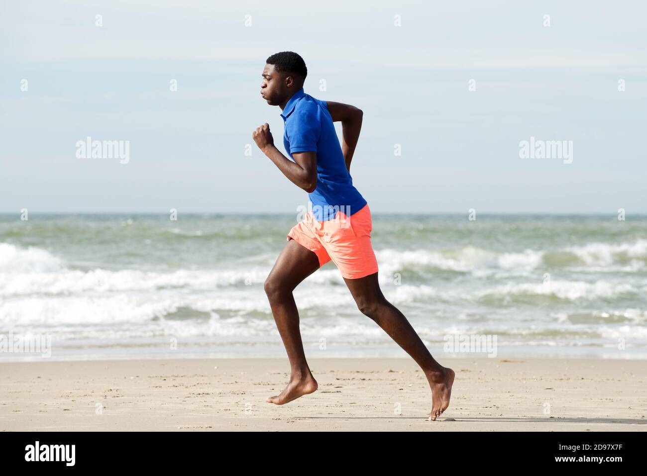 Full body healthy african american man running barefoot at beach Stock ...