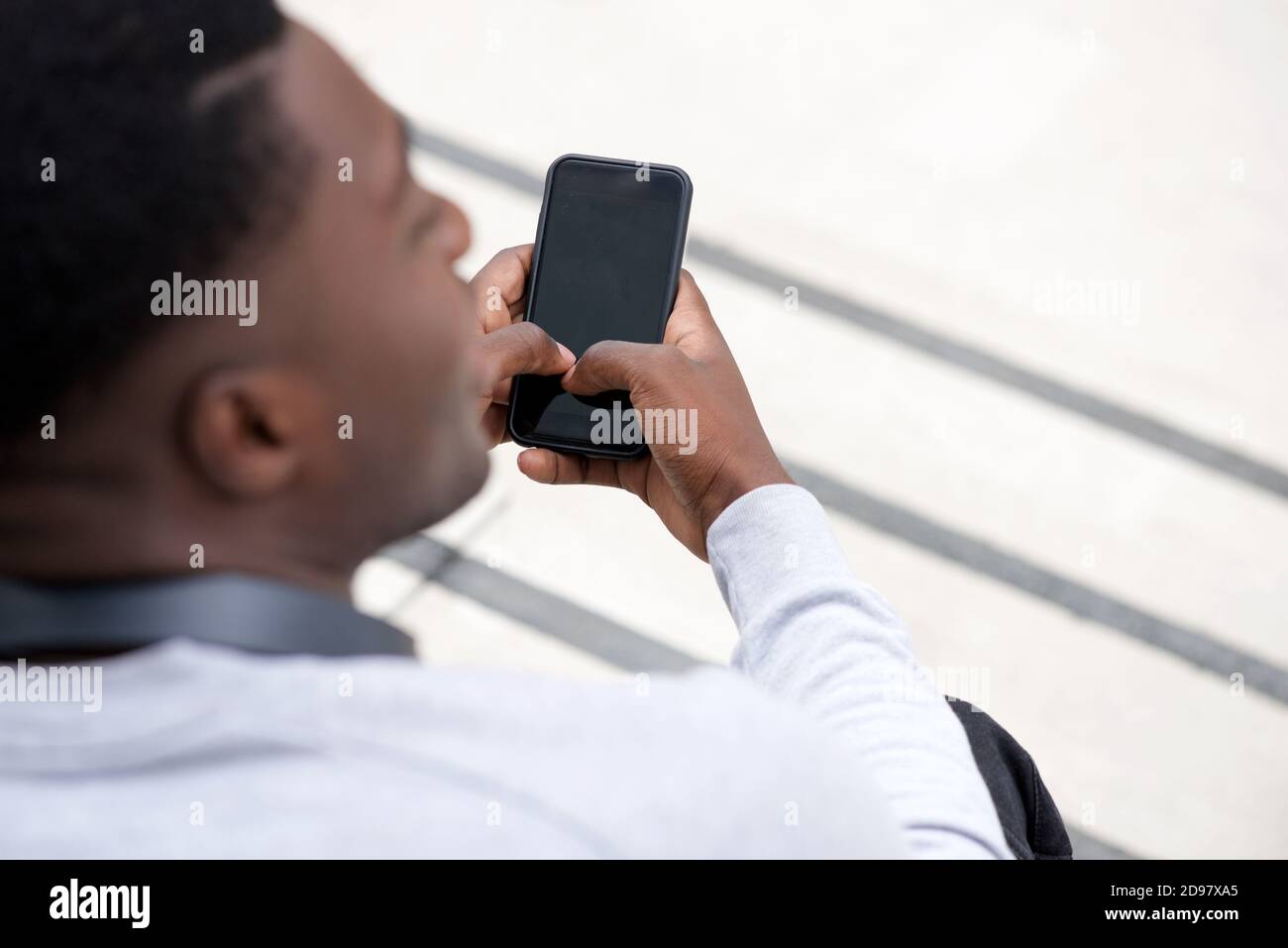 Close up portrait from behind of young black man holding smart phone ...