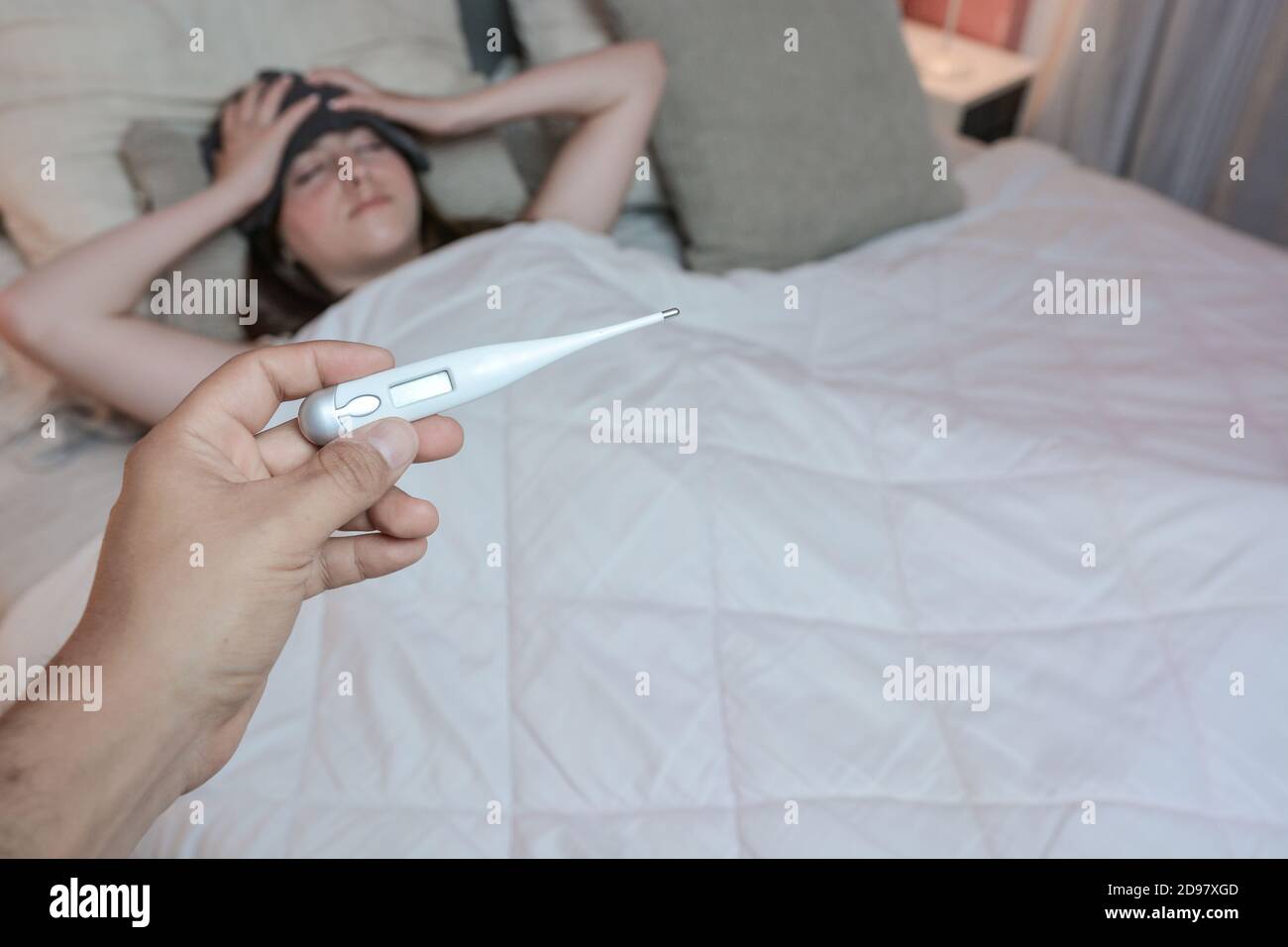 Sick teenage girl with a high fever and a thermometer. She has a cold ...