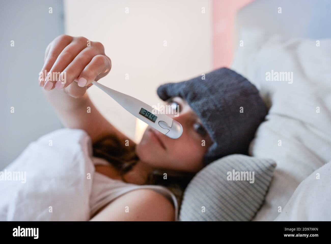 Sick teenage girl with a high fever and a thermometer. She has a cold ...