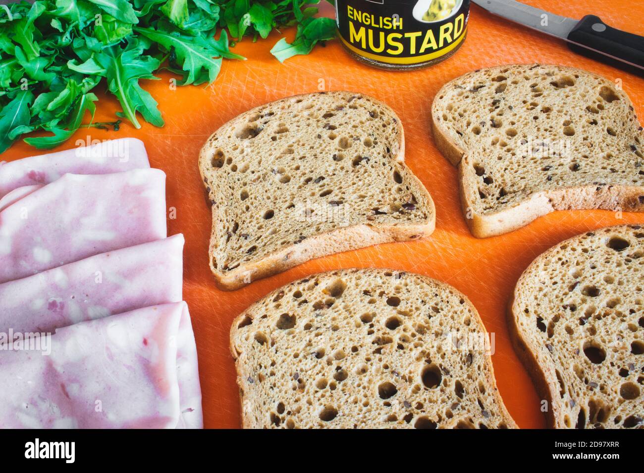 Slices of wholemeal brown bread laid out on a chopping board with ham ...