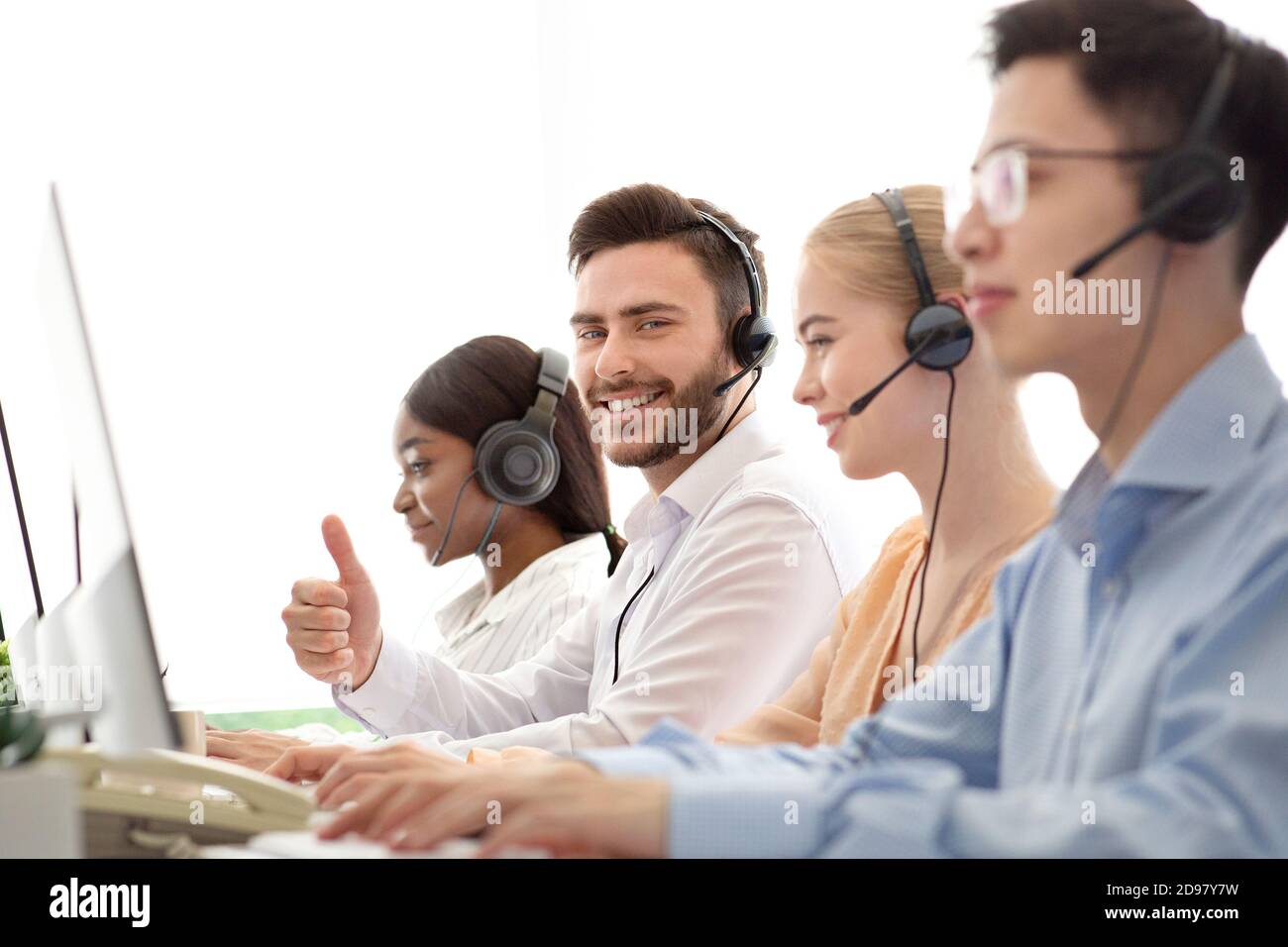 Happy male call centre operator showing thumb up gesture, working with ...