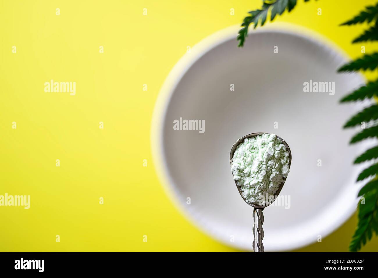 A glass of water, collagen powder on a bright yellow background ...