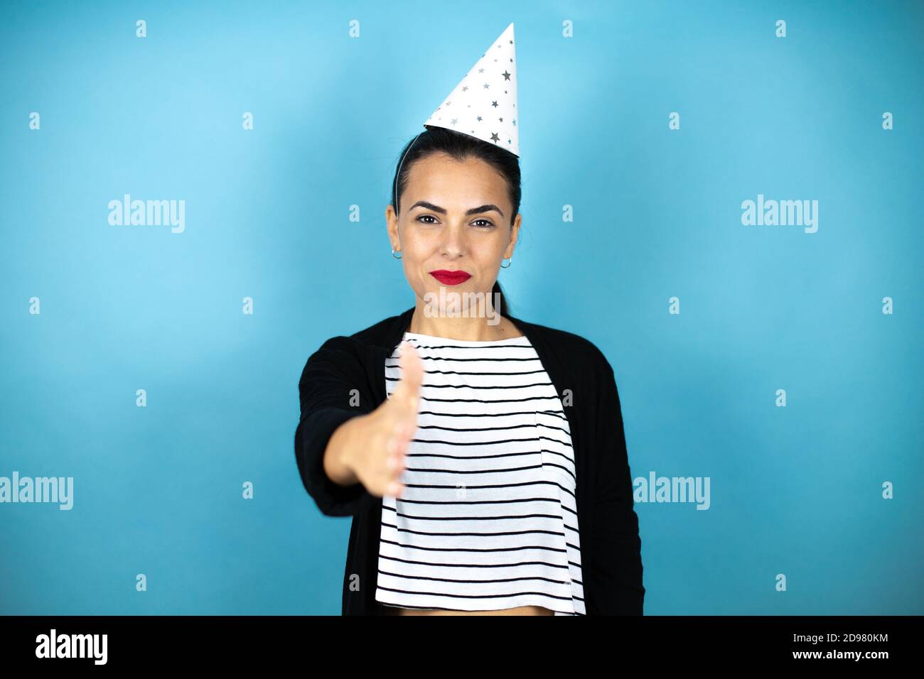 Young beautiful woman wearing a birthday hat over insolated blue ...