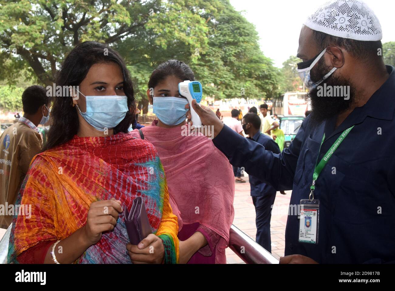 A security personal checks the body temperature of visitors during ...