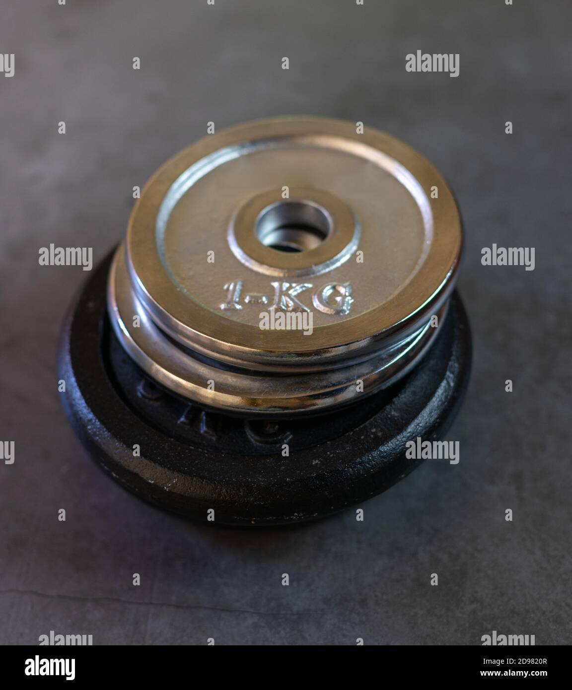 Iron weight plates of different sizes and weights stacked on a concrete ...