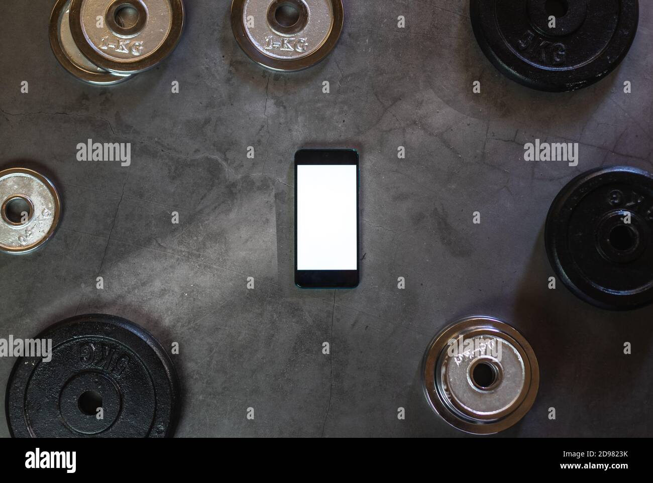 Mobile phone on a concrete surface with weight plates of different ...