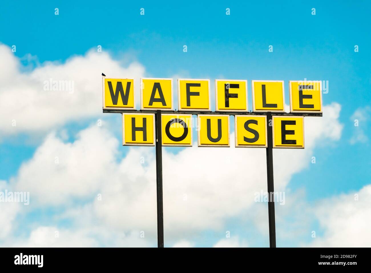 Waffle house roadside sign set against a blue sky with clouds in the ...