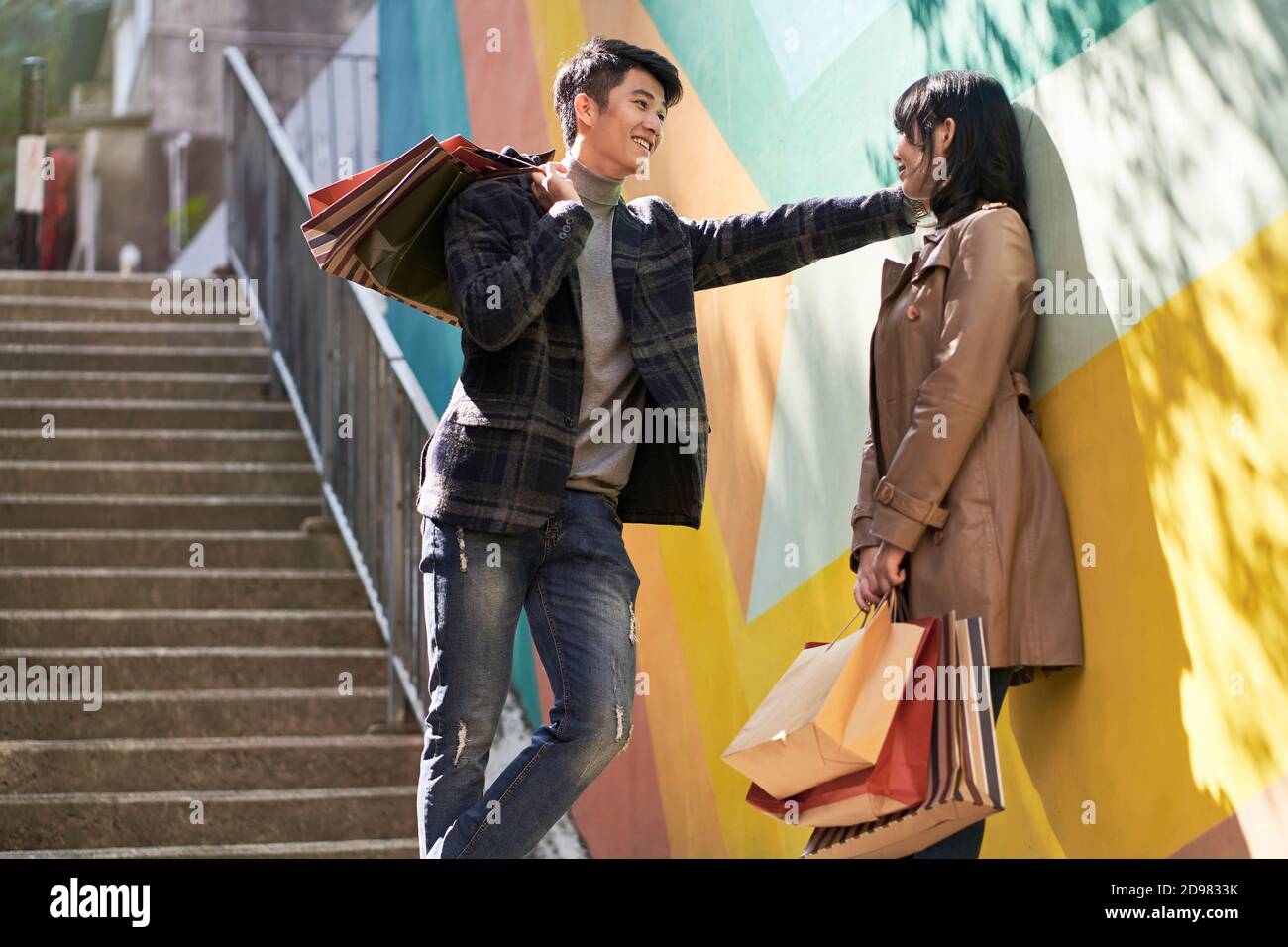 young asian couple lovers shoppers standing talking relaxing outdoors ...