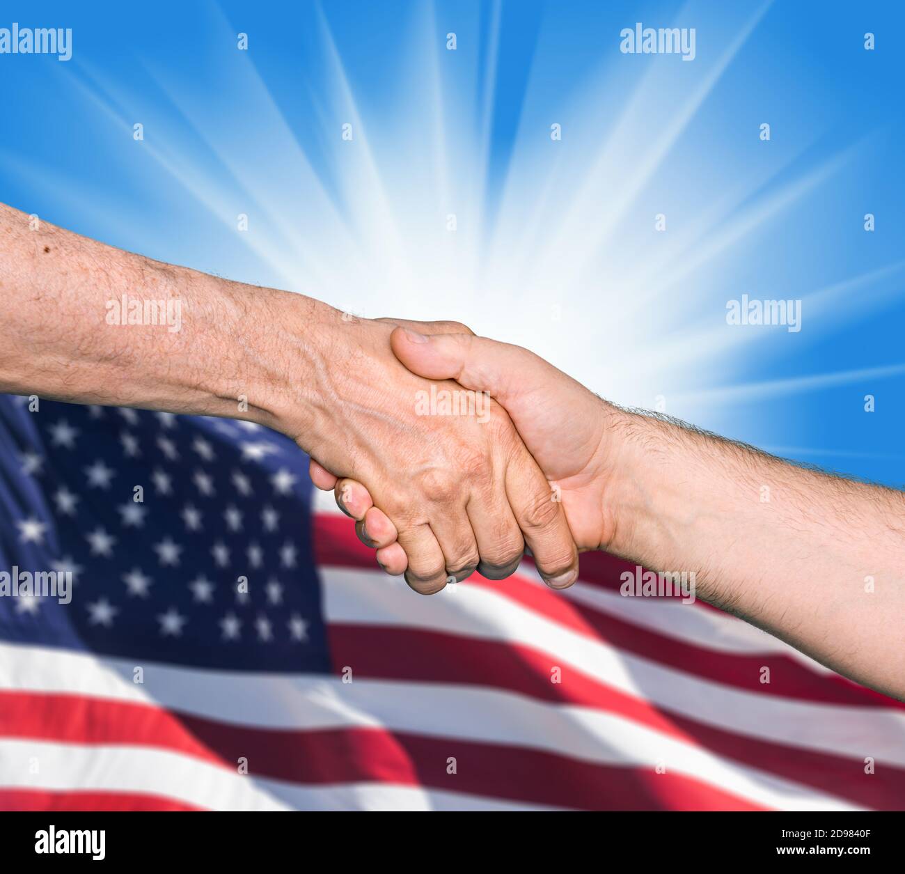 The USA flag and shaking hands of two male people on blue sky ...