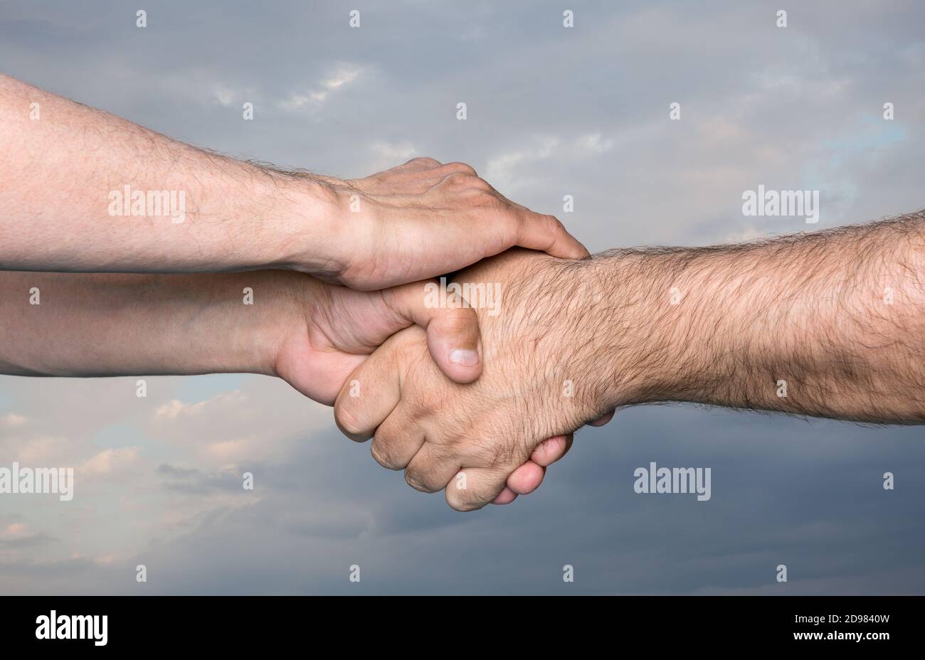 Handshaking. Shaking hands of two male people against the sky with ...