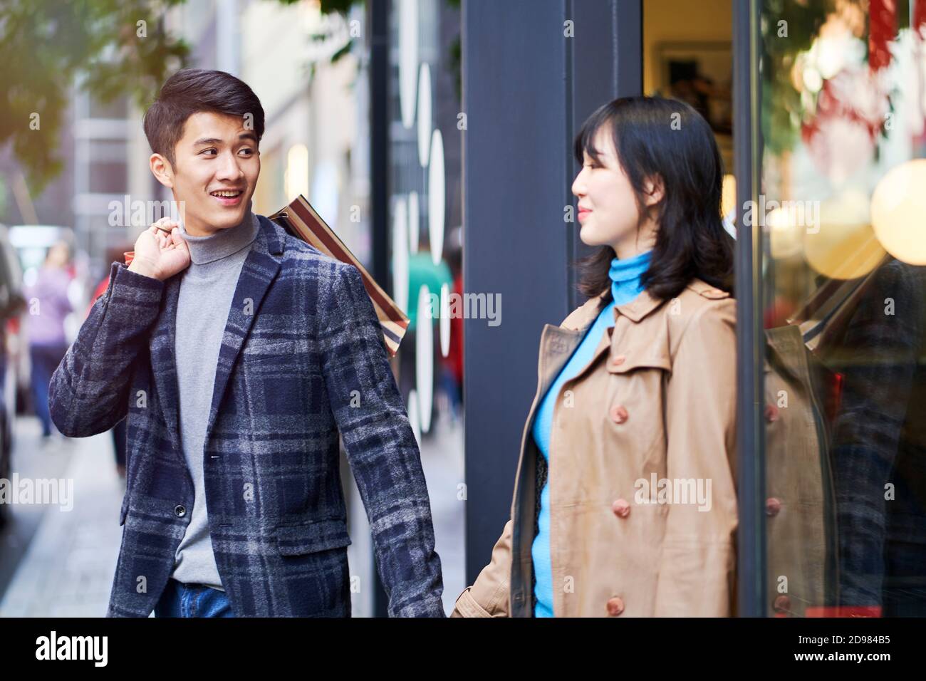 happy young asian couple shopping in city exiting a modern store on ...