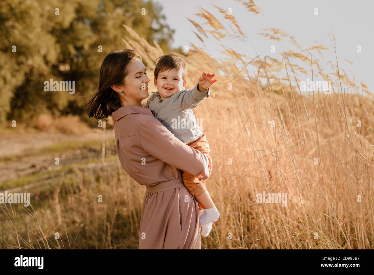 Portrait of happy loving mother hugging her baby son in the sunny park ...