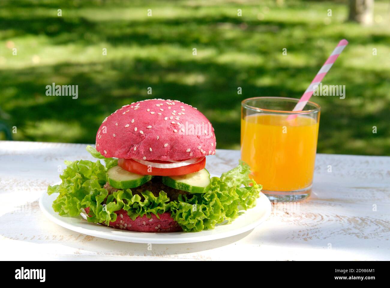 Pink hamburger and orange juice on white table in the garden Stock ...
