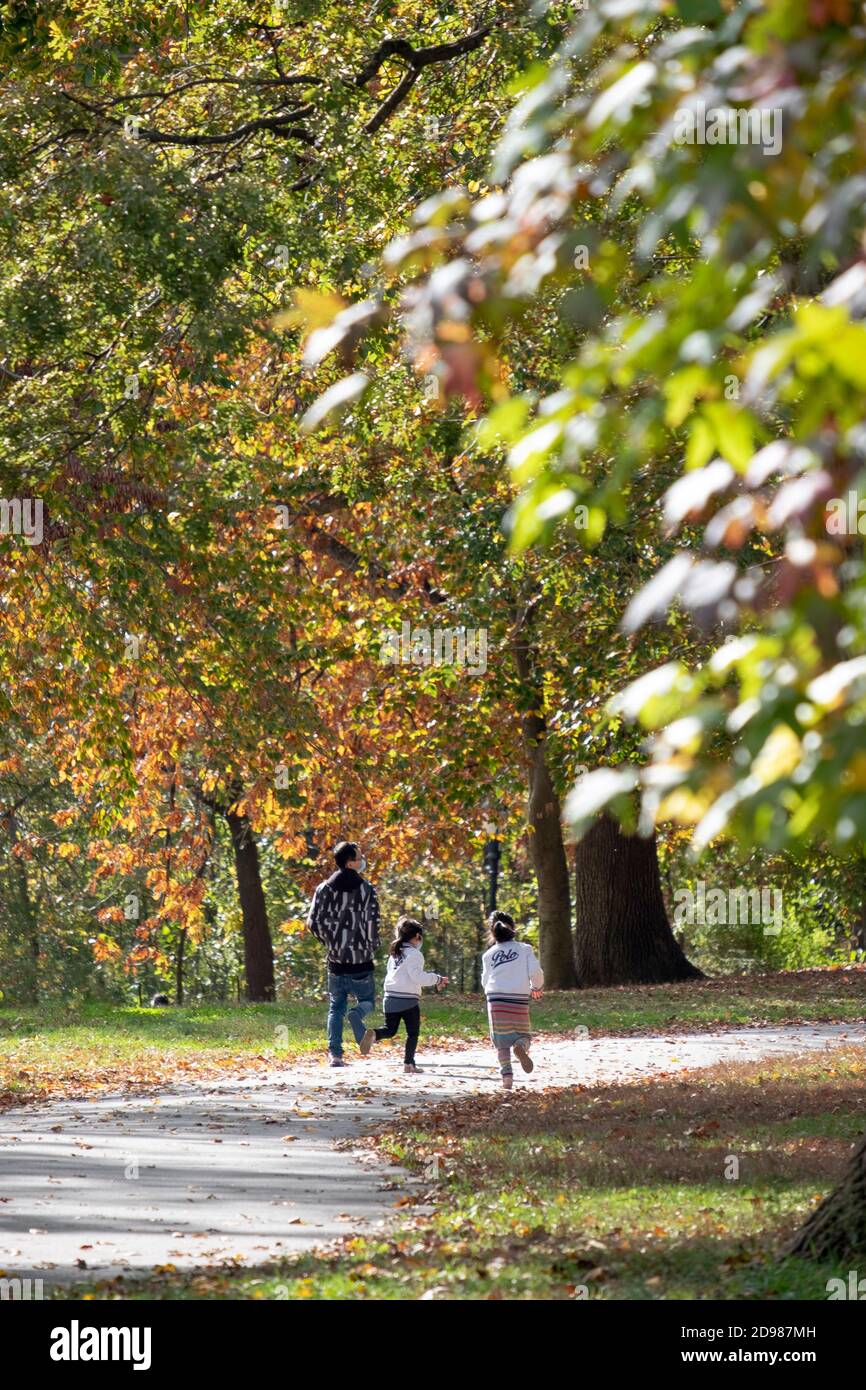 A family walks through Kissena Park amidst the beautiful fall colors ...