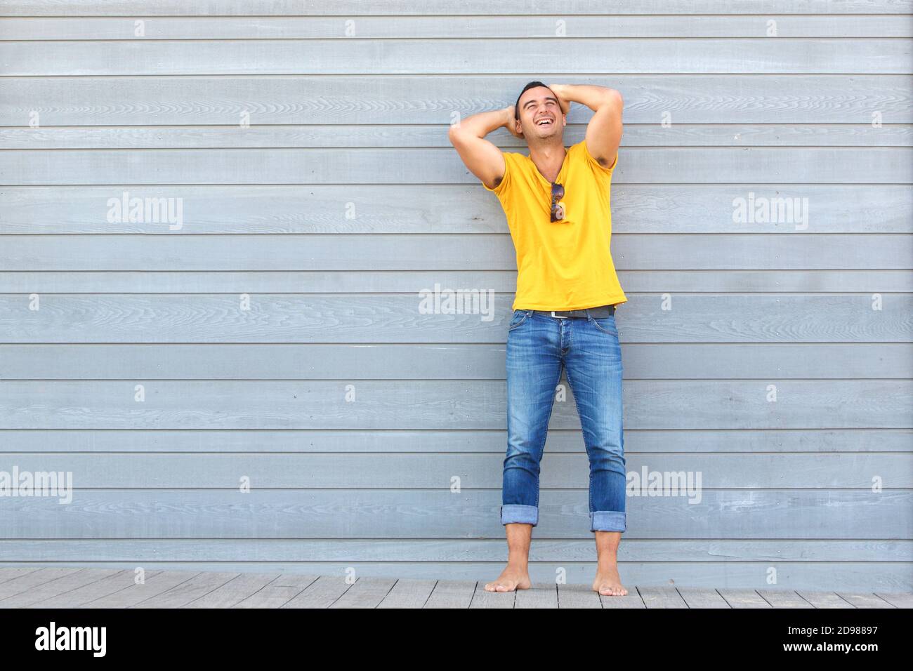Full body portrait of happy man posing with hands behind head against ...