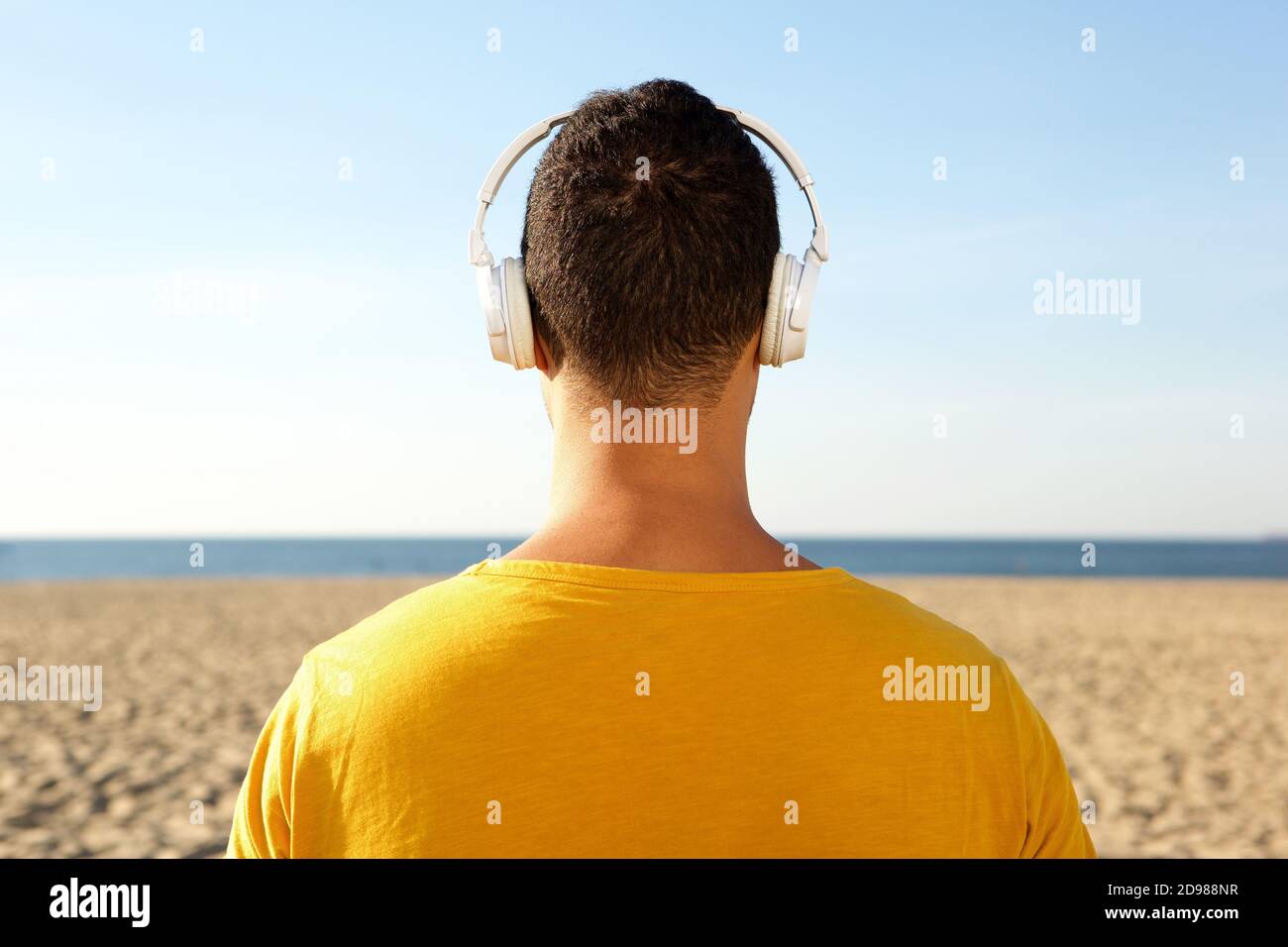 Portrait from behind of man listening to music with headphones at the ...