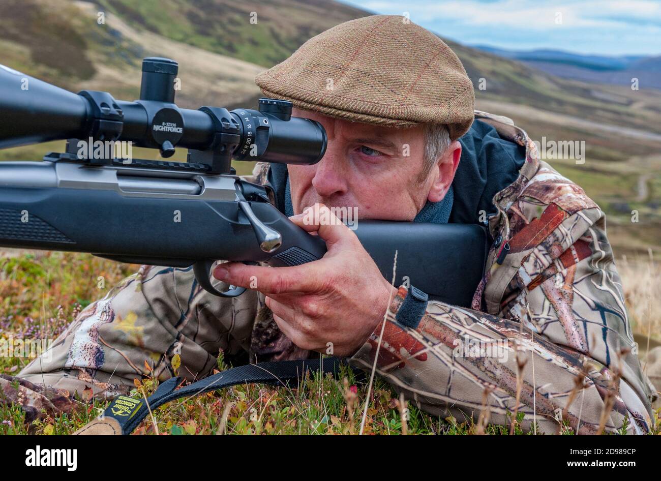 Scotland, UK – A deerstalker in the Scottish Highlands looking for a ...