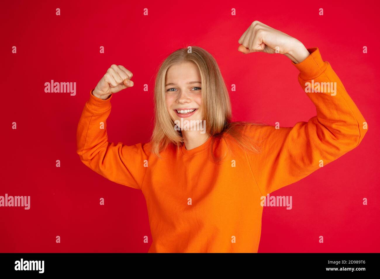 Strong, power. Portrait of young caucasian woman isolated on red studio ...