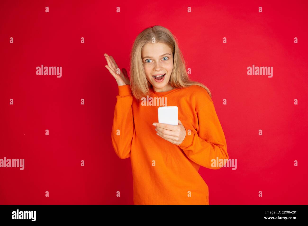 Shocked, wondered with phone. Portrait of young caucasian woman ...