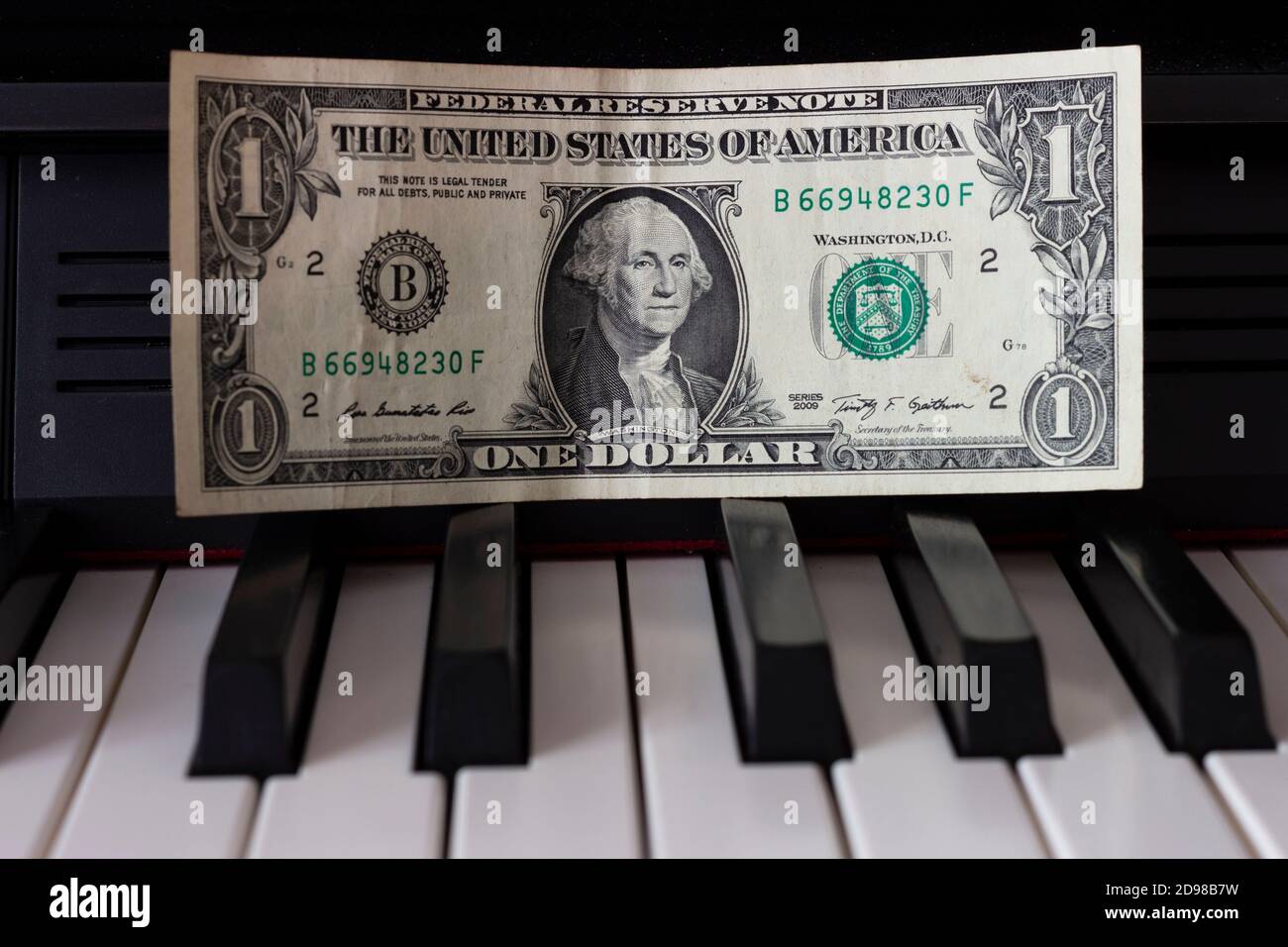 One dollar banknote lying on the piano keys. The dollar as a symbol of ...